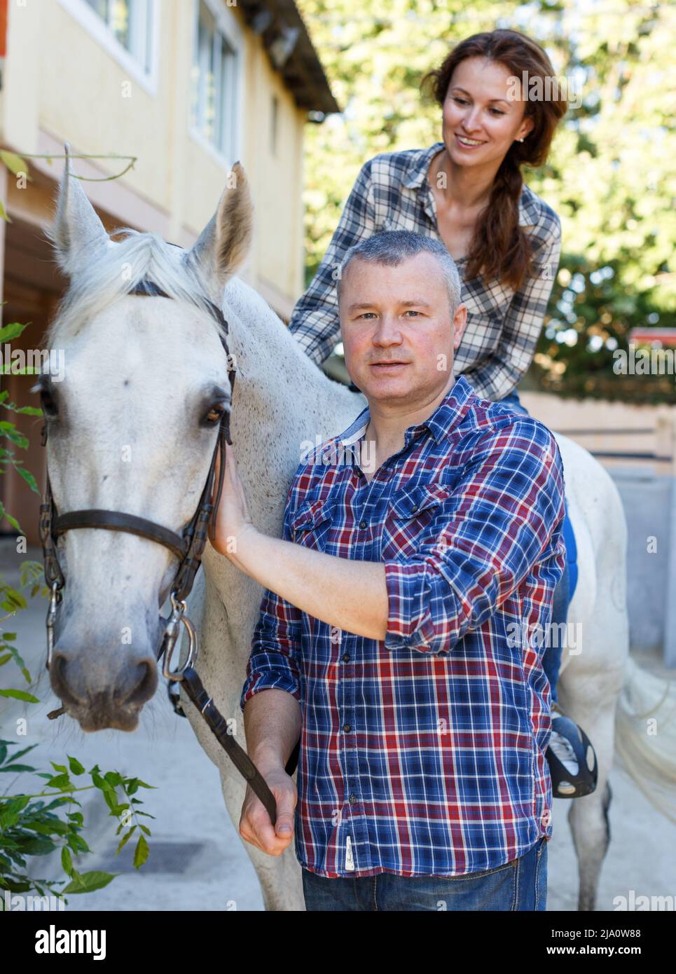 Man trainer teach to female while riding horse at ranch Stock Photo - Alamy