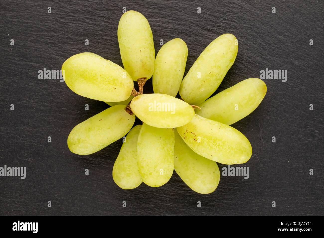 One bunch of seedless white grapes on a slate stone, close-up, top view ...