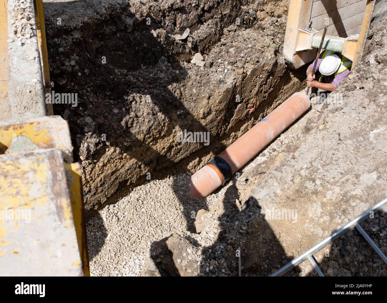 Ground workers installing new clay drainage pipe during deep drainage ...