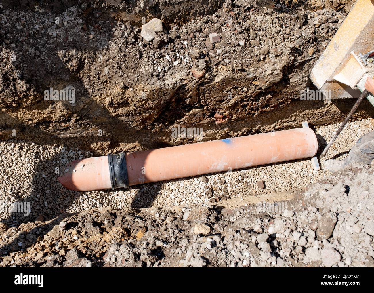 Ground workers installing new clay drainage pipe during deep drainage ...