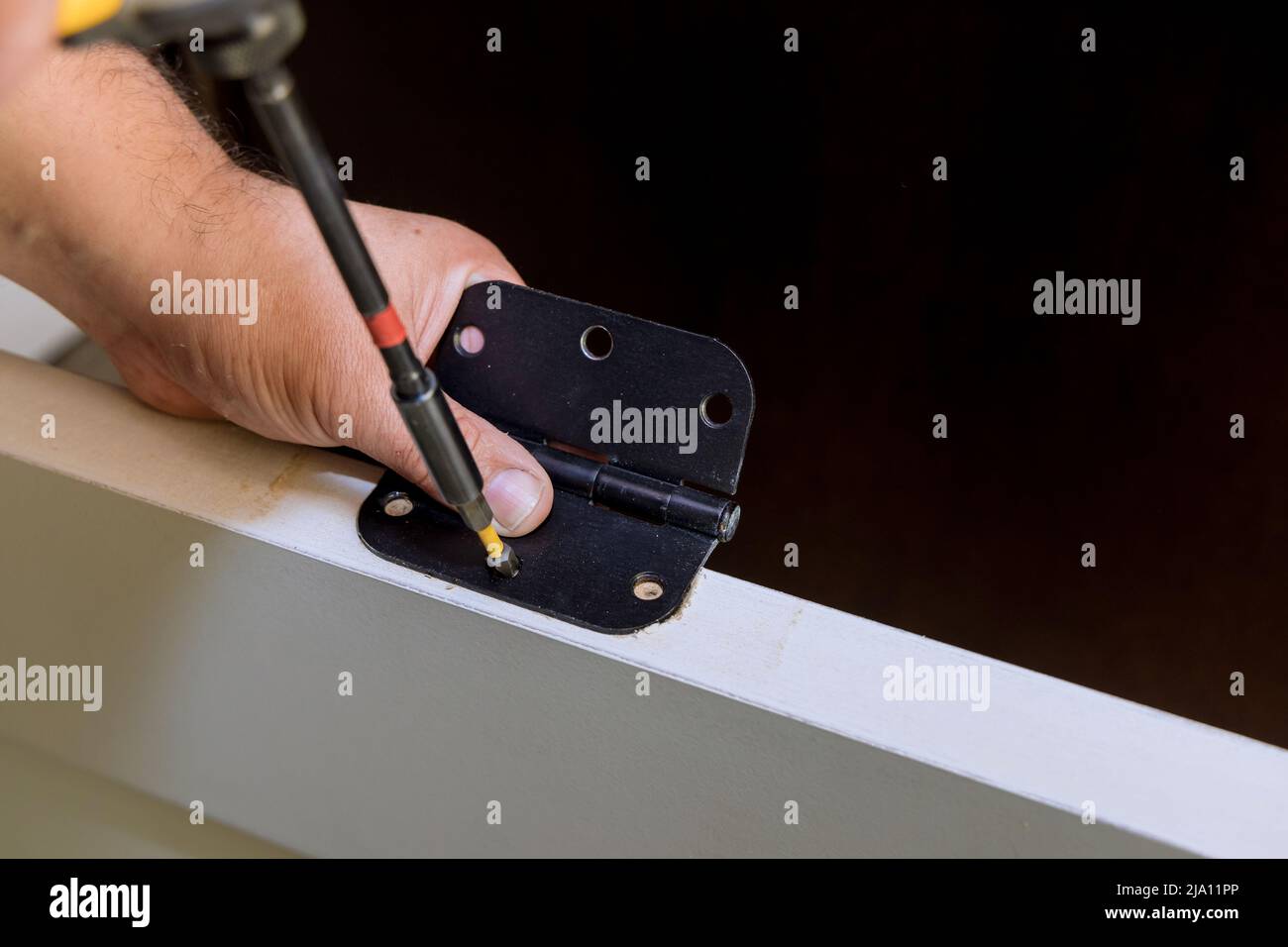 Man installing stainless door hinges the door screw with a screwdriver ...
