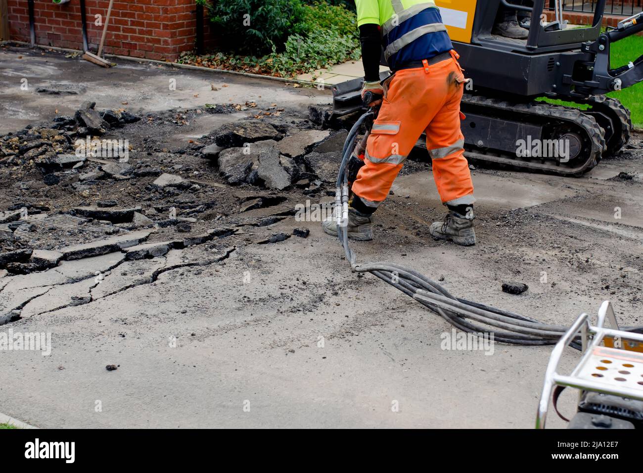 Construction worker breaking road gully using hydraulic breacker during ...