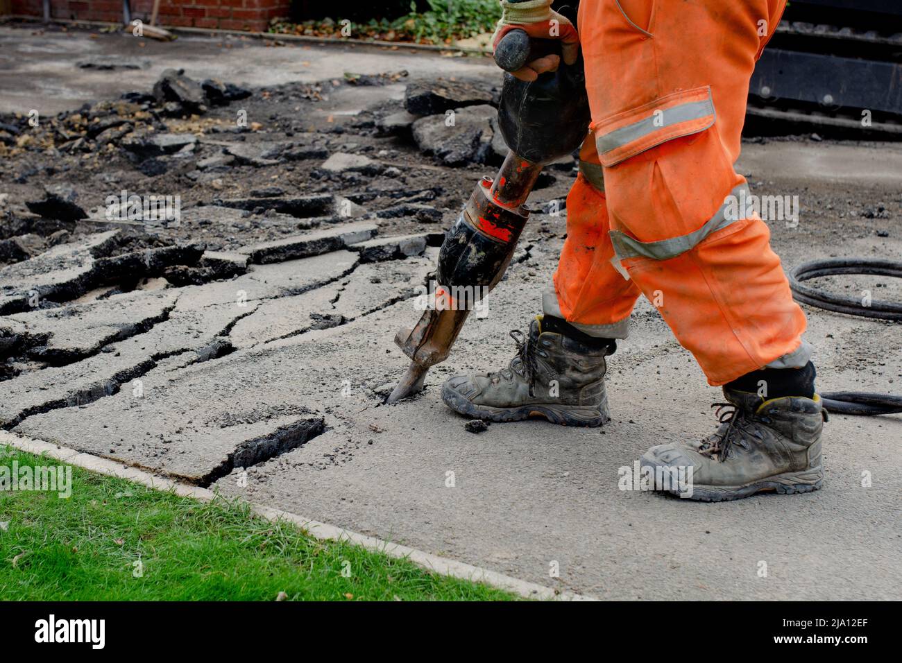 Construction worker breaking road gully using hydraulic breacker during ...