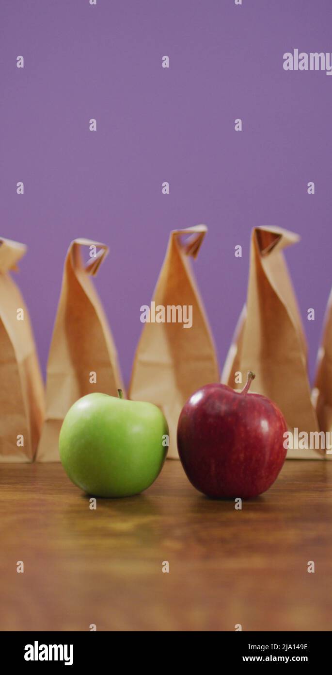 Vertical image of red and green apple with row of packed lunches in ...