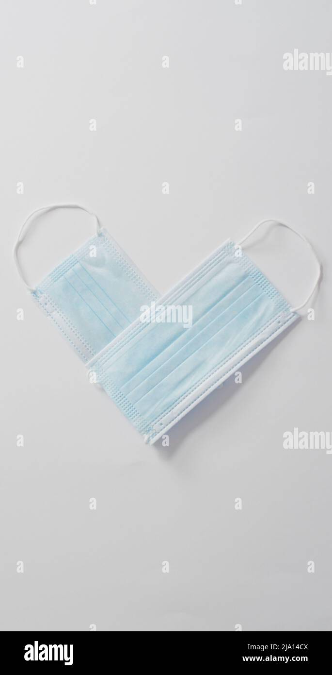 Vertical image of overhead view two face masks forming heart shape on ...