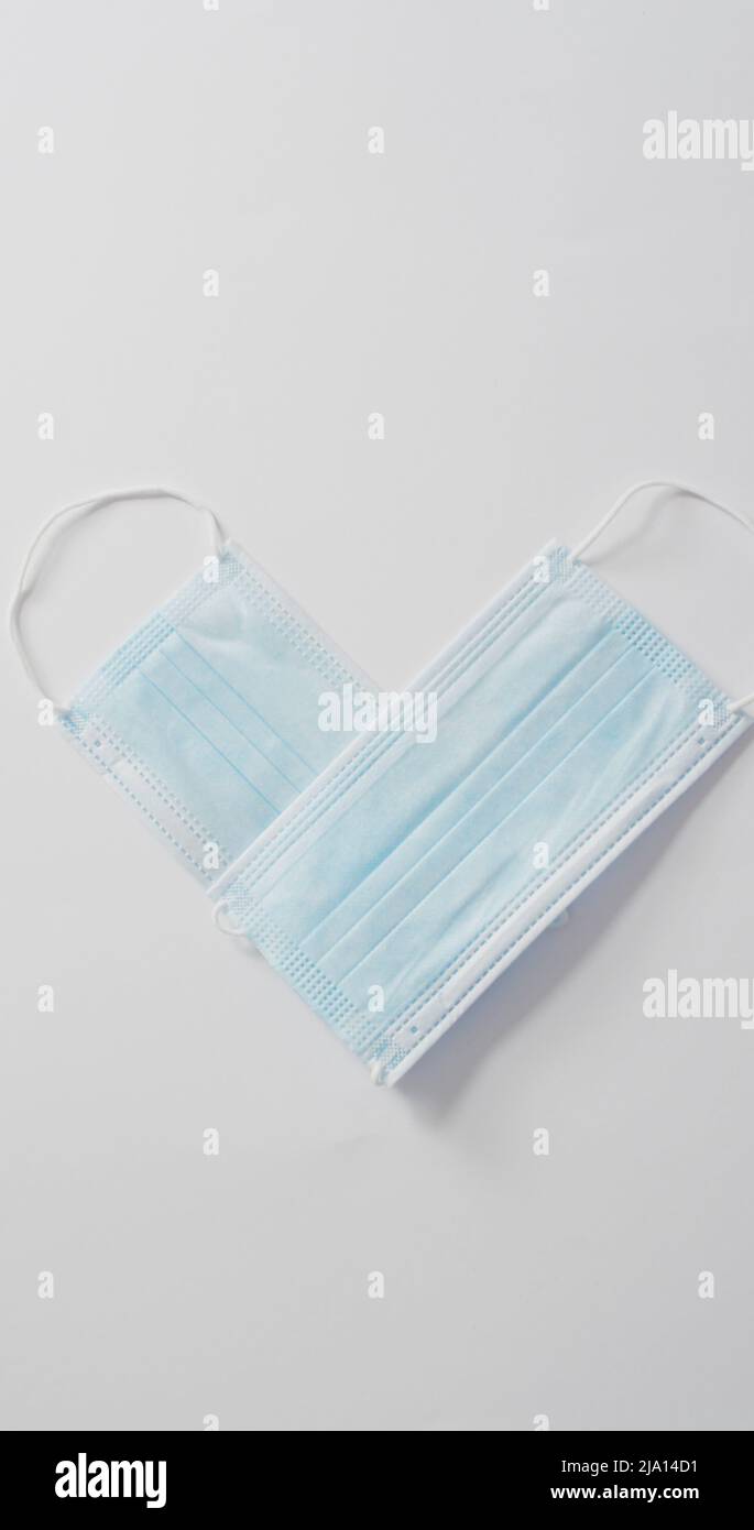 Vertical image of overhead view two face masks forming heart shape on ...