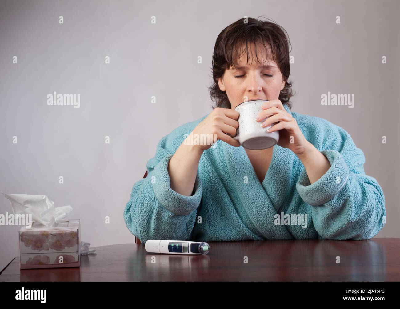 Woman in a bathroom with a bad cold holding a mug Stock Photo - Alamy