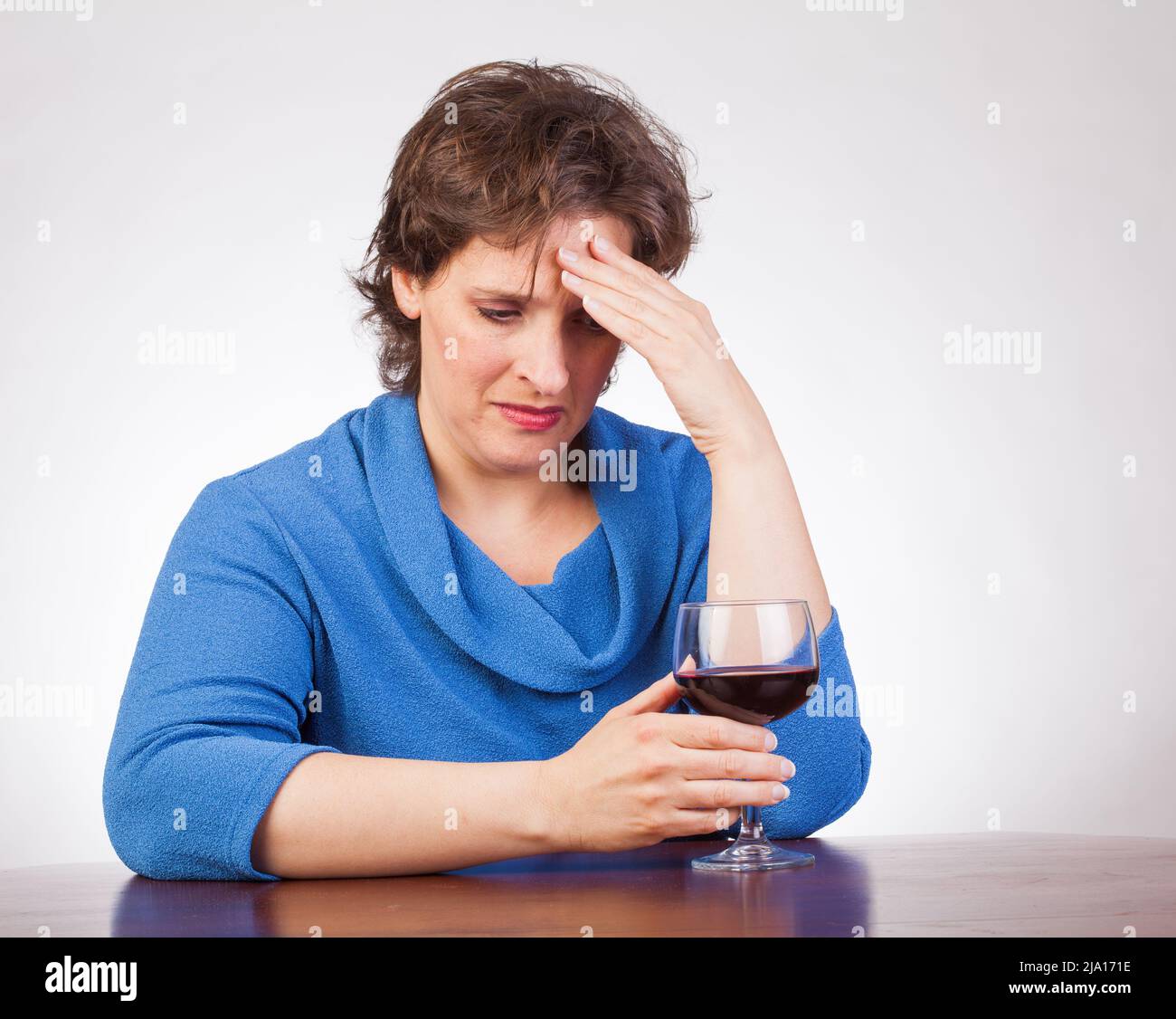 40 something woman staring at a glass of wine looking very upset Stock ...