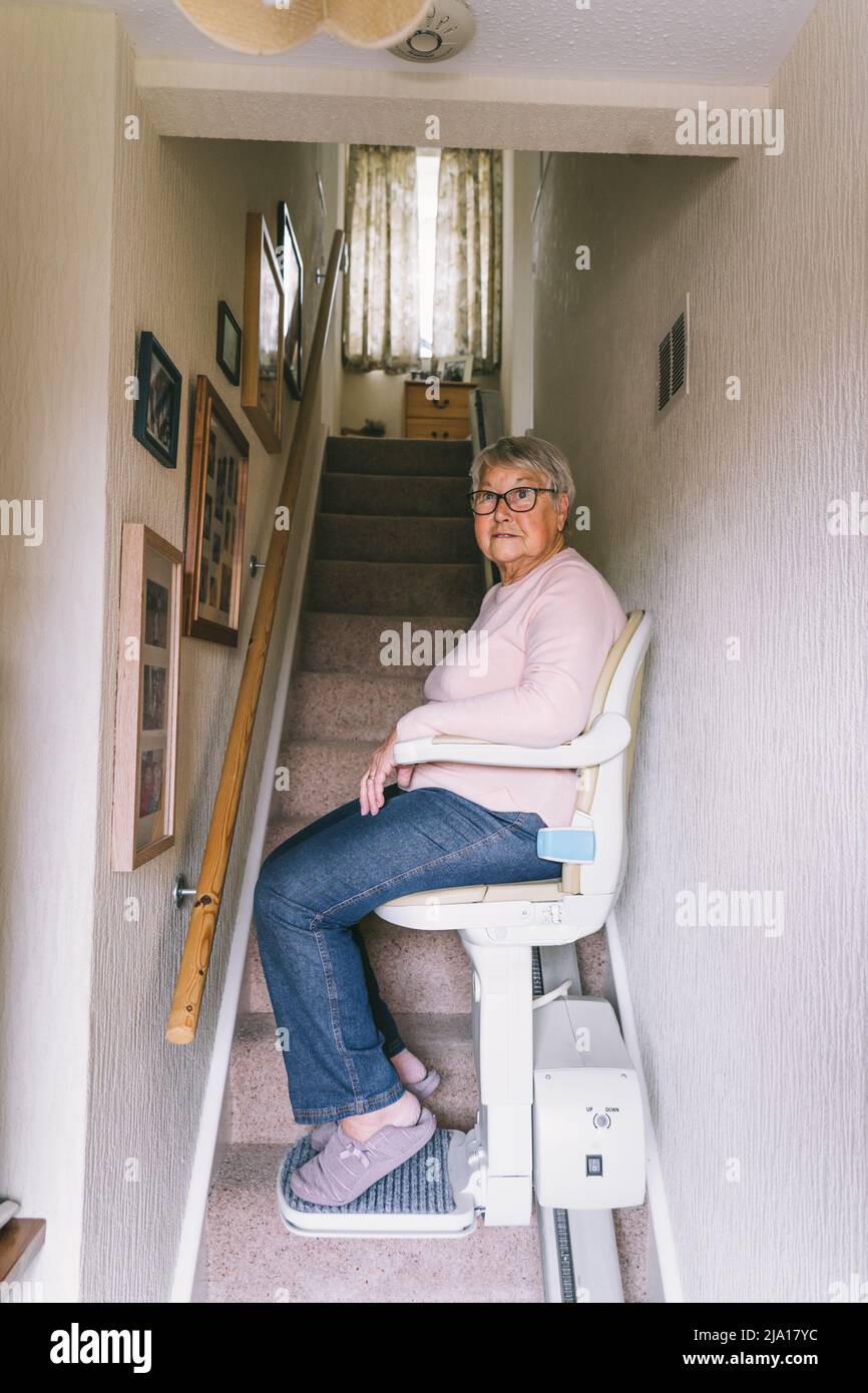 Senior woman using automatic stair lift on a staircase at her home ...
