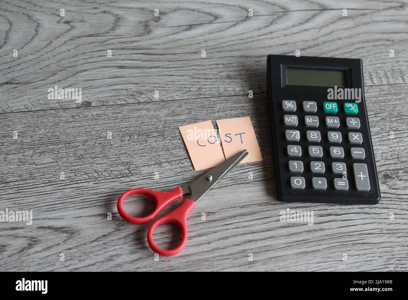 Scissor, calculator and note with text COST. Financial, cost cutting ...