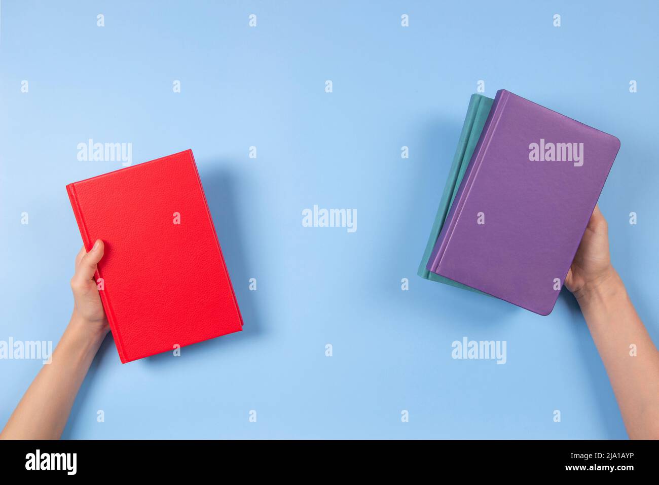 Hands holding books over light blue background. Education, self ...