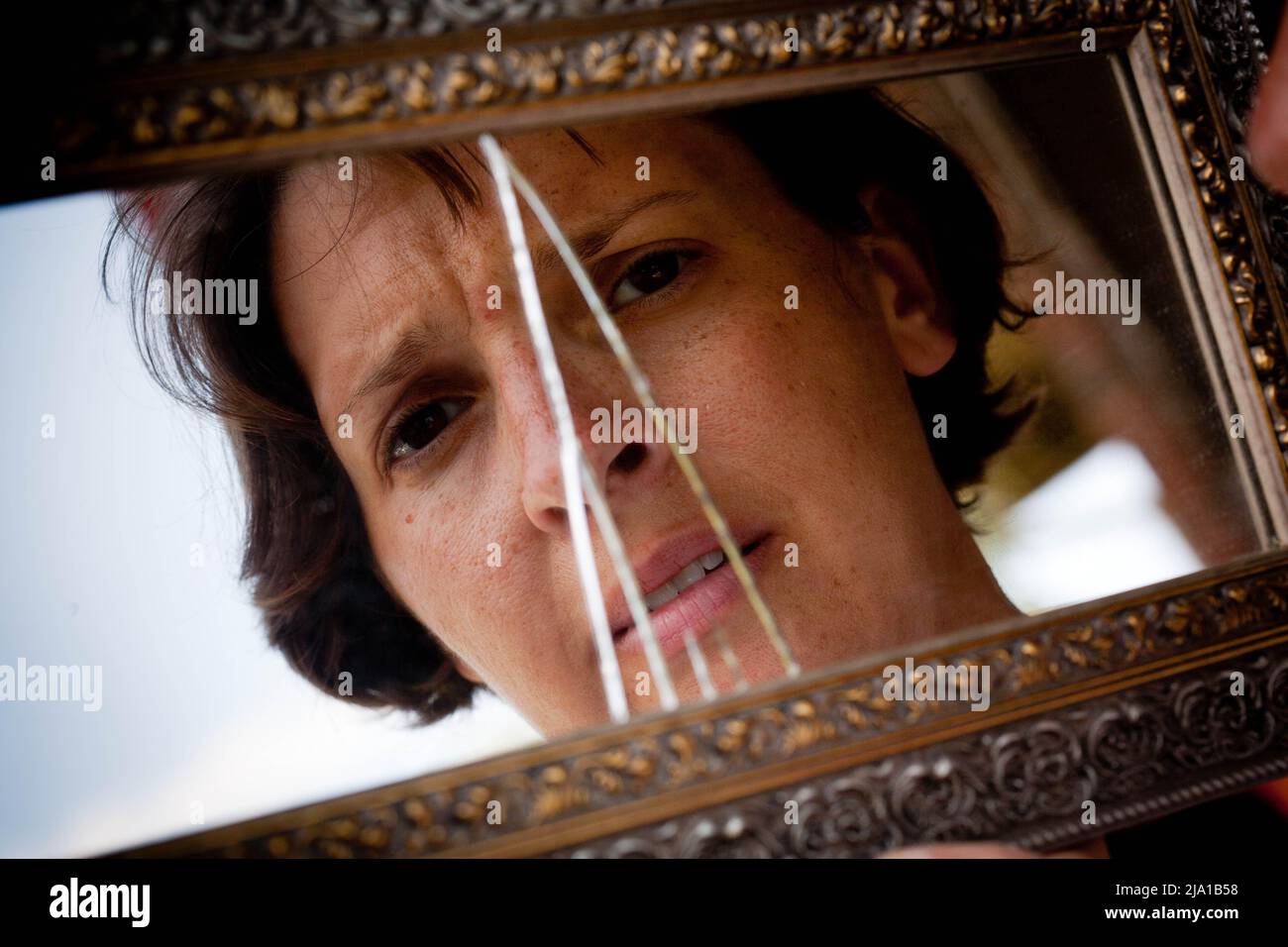 Woman looking sad and lost through a broken mirror Stock Photo - Alamy