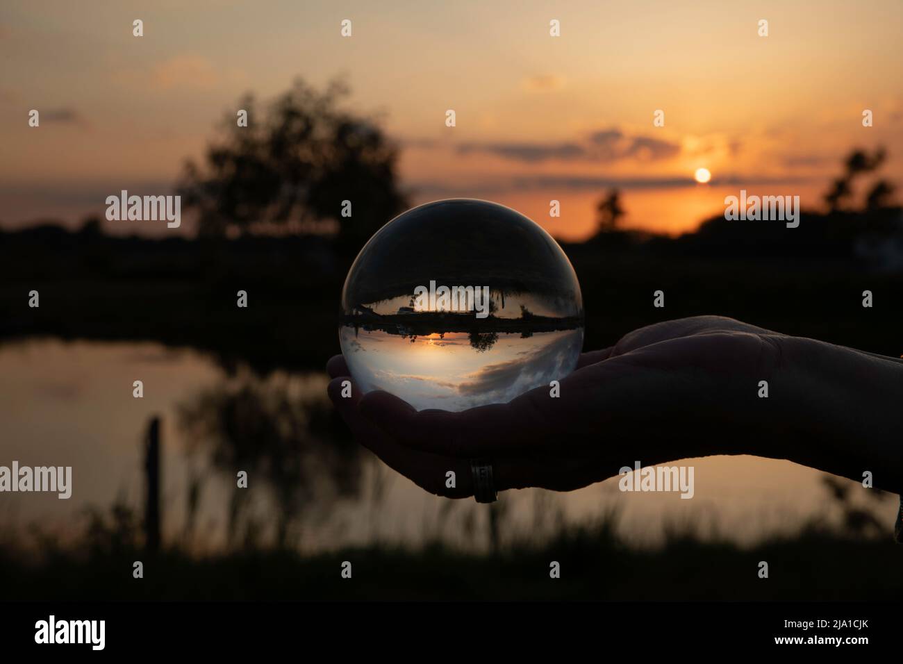sunset in a glass ball in womans hand Stock Photo - Alamy