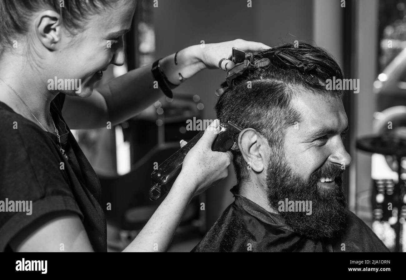 attractive barber making haircut of handsome guy in barbershop ...