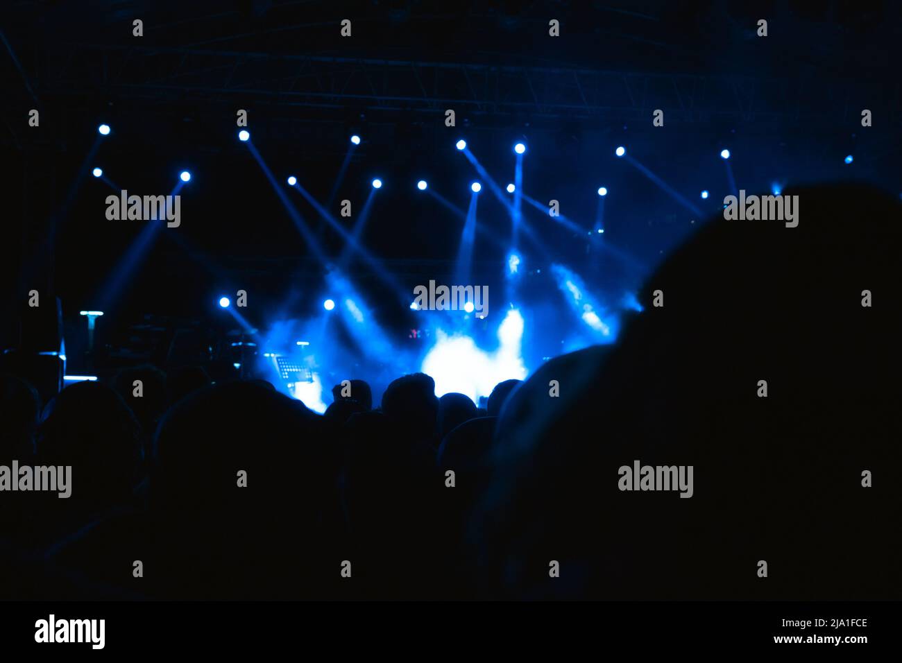 Silhouette of People in the concert area with spotlights on the stage ...