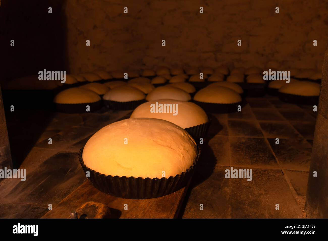 Close-up of bread dough in molds is sent to a shovel in a stone ...