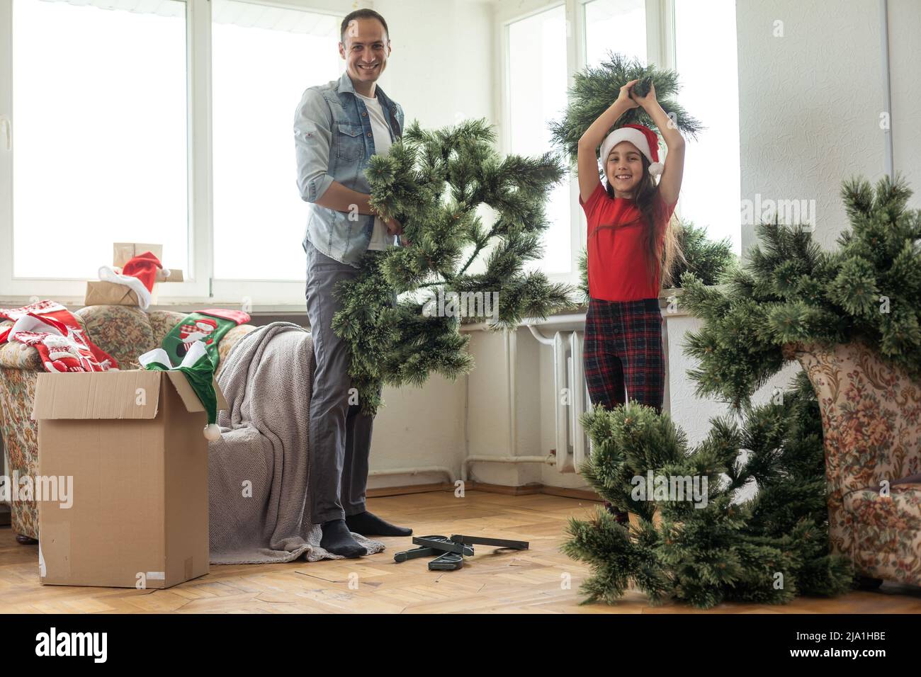 father and daughter install an artificial Christmas tree Stock Photo ...
