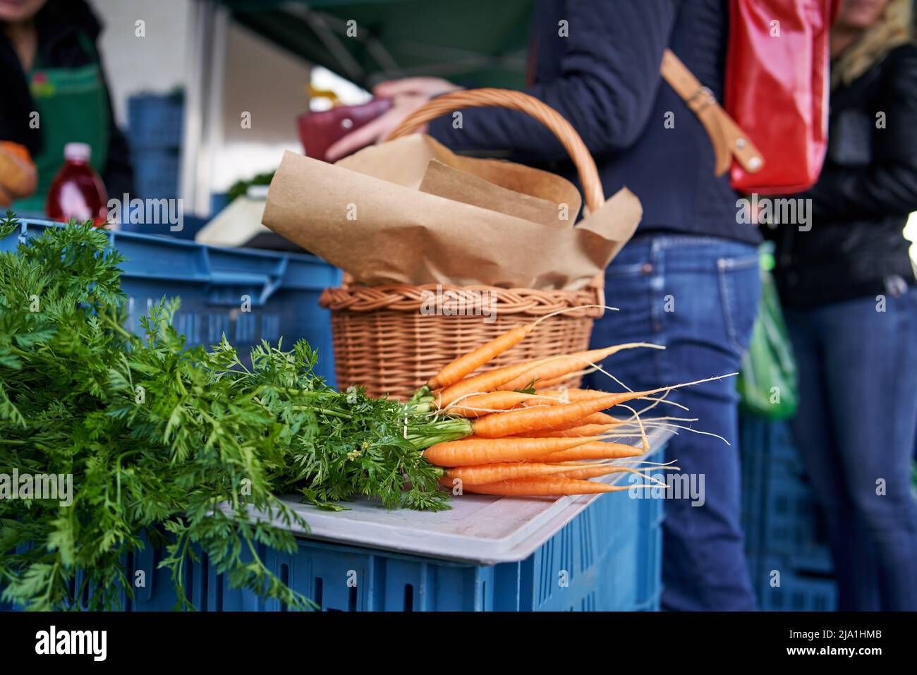 Fresh carrots lying on crates at the farmers market, with a woman ...