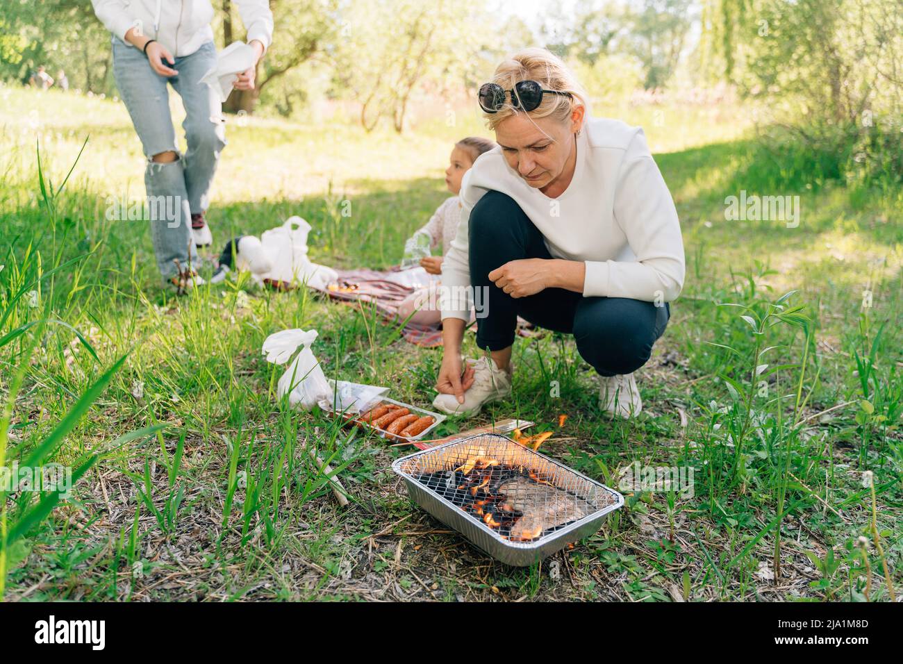 Family with small child, teen and grandmother doing bbq on the nature ...