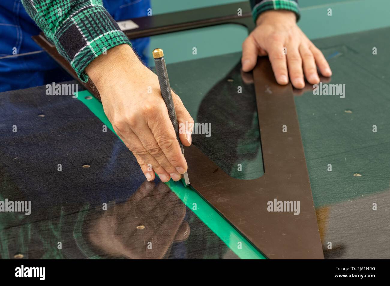 cutting glass, Glazier manually cuts the glass to size using ...