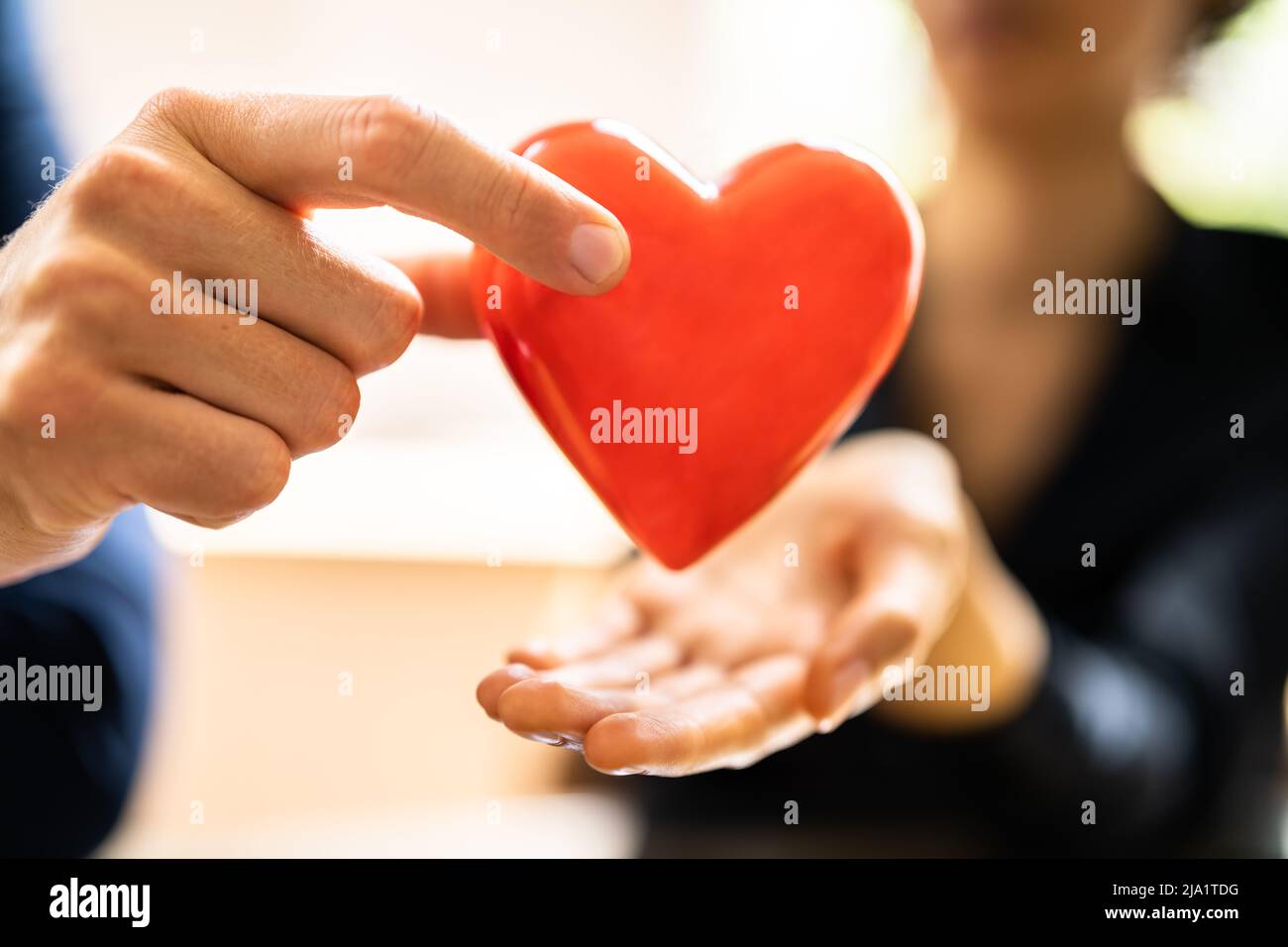 Male Hand Giving Heart Shape To Female Stock Photo - Alamy