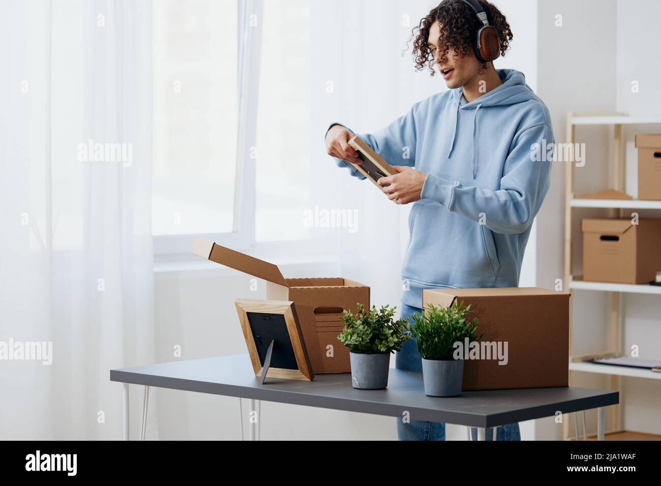 handsome guy cardboard boxes in the room unpacking in headphones ...