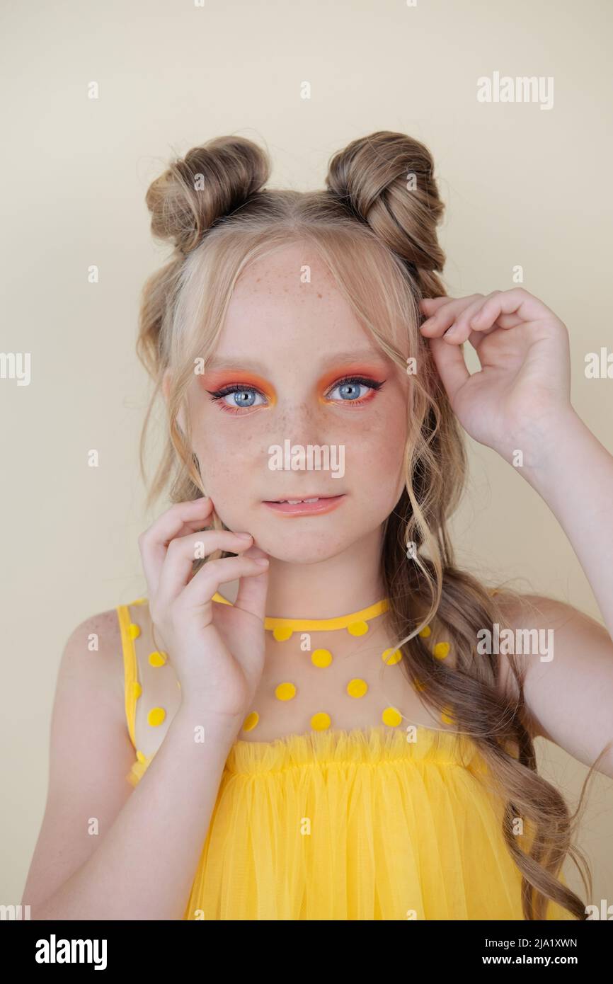 charming blonde tween girl with orange makeup on yellow background ...