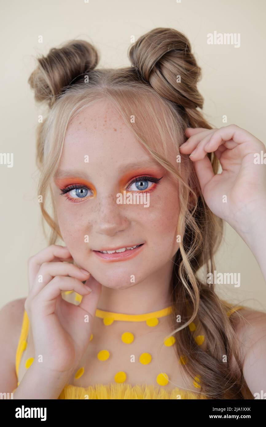 charming blonde tween girl with orange makeup on yellow background ...