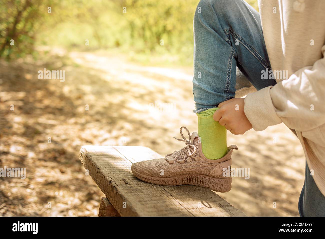Child tying up laces his sneakers in spring park for walk. Girl ties ...