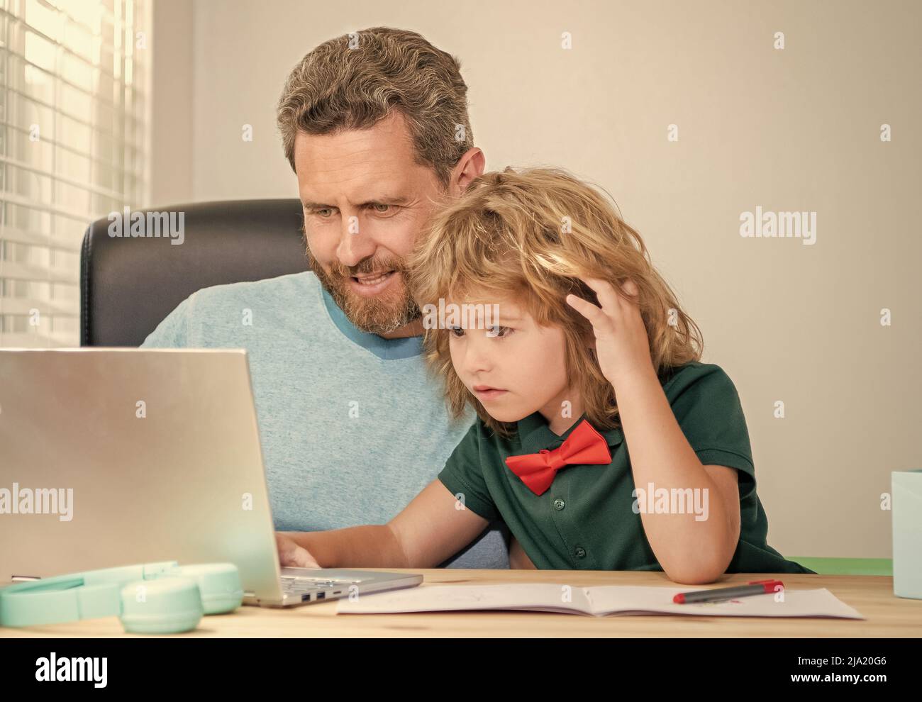 happy attentive father and child son at school working online on laptop ...