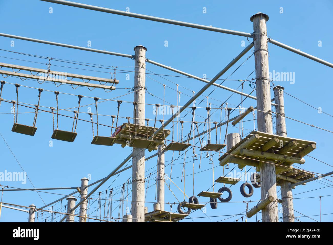 Adventure climbing high wire park with wooden poles under a blue sky ...