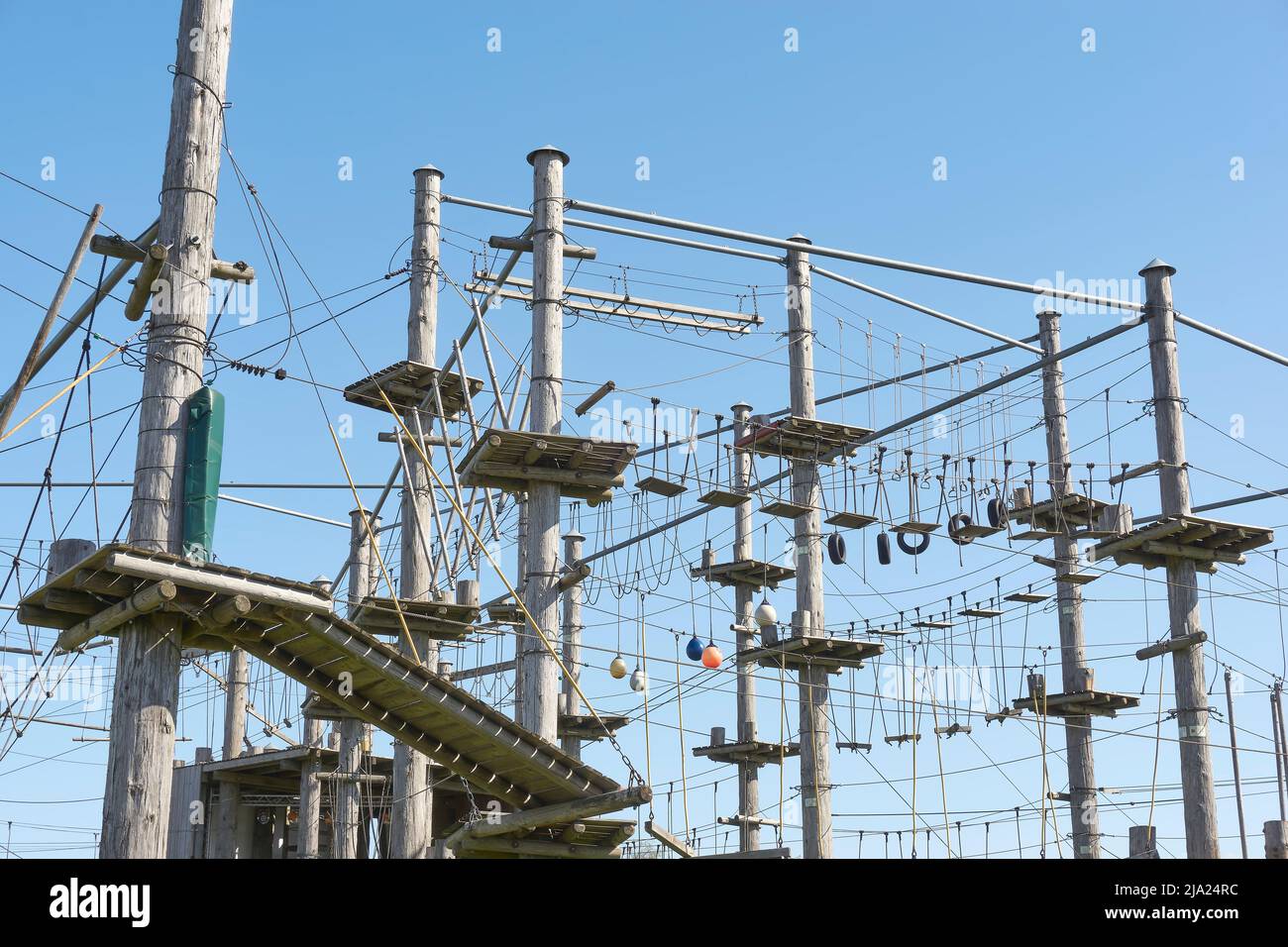 Adventure climbing high wire park with wooden poles under a blue sky ...
