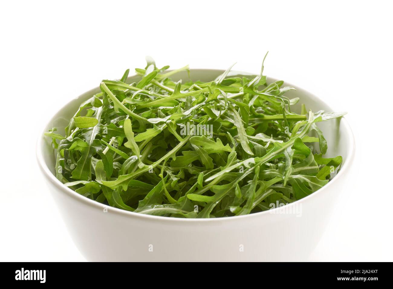 Fresh green arugula or rucola leaves in a white bowl isolated on a ...