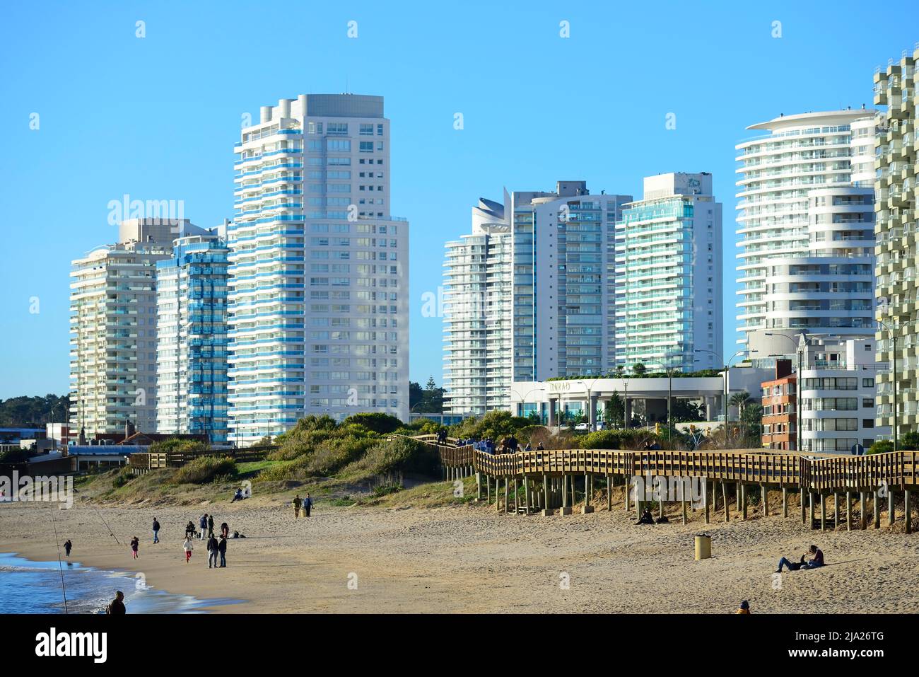Wooden jetty on the beach in front of high-rise buildings with flats ...