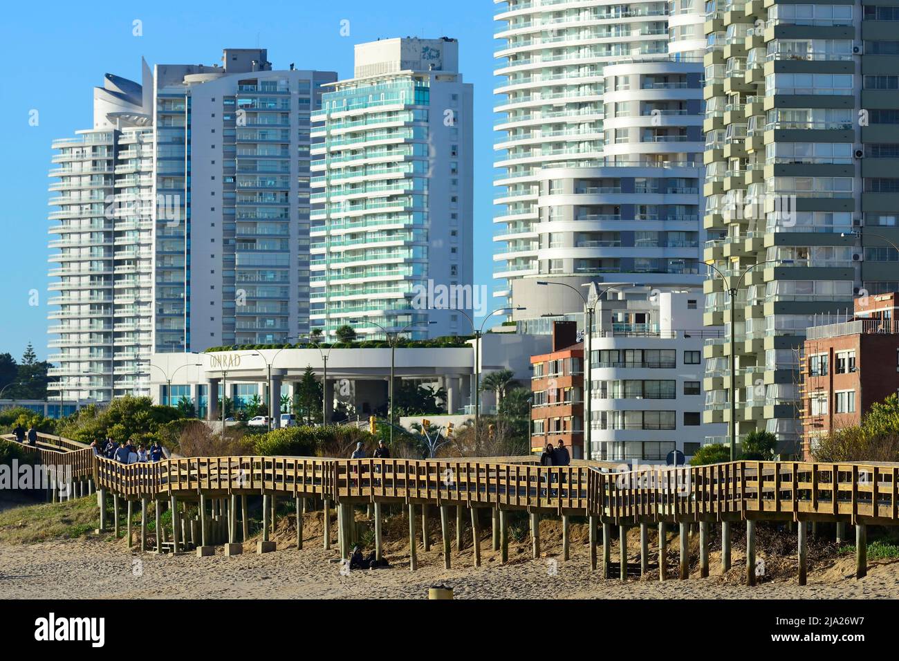 Wooden jetty on the beach in front of high-rise buildings with flats ...