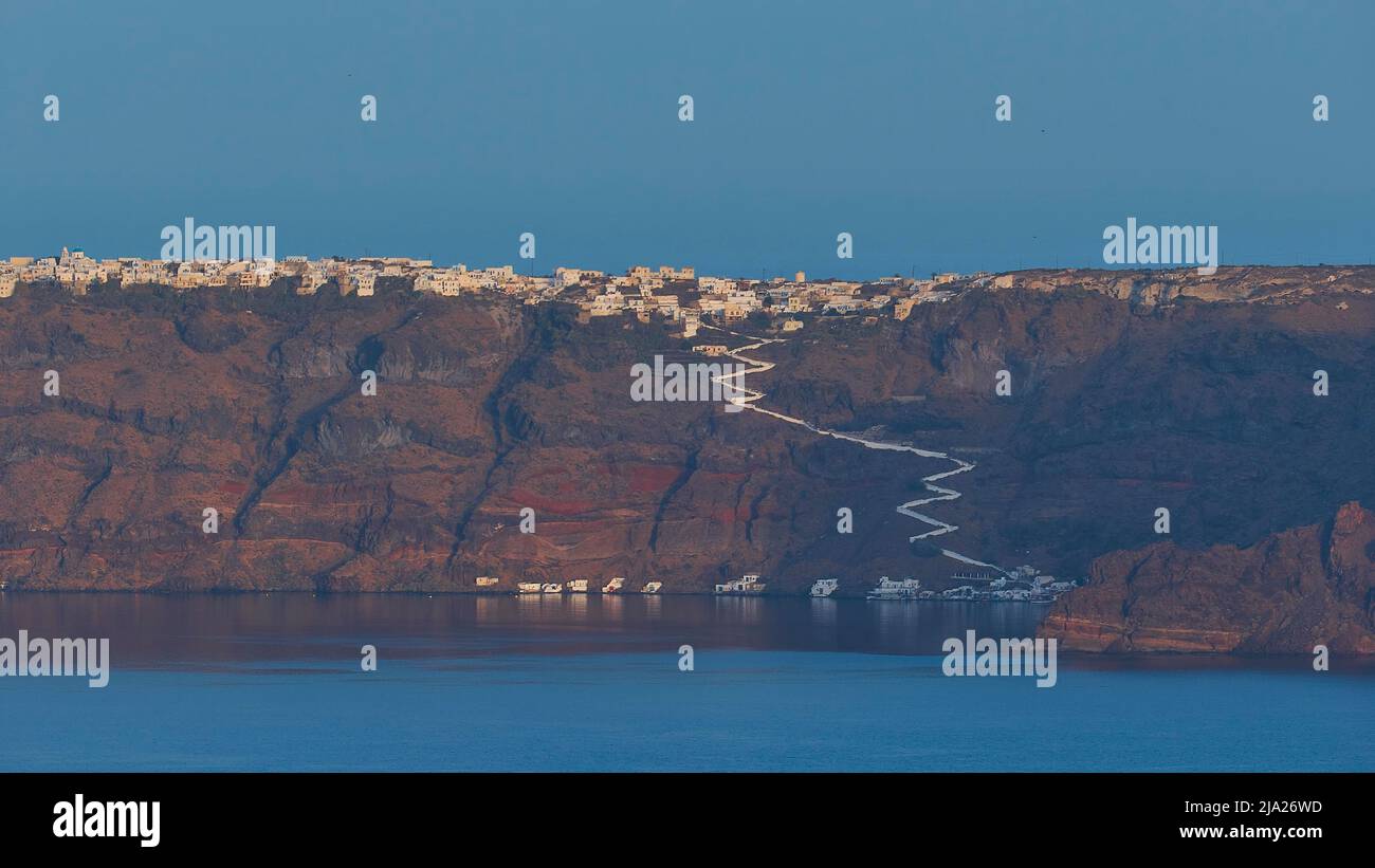 Morning light, cliffs, red lava rocks, houses, white paved path up ...