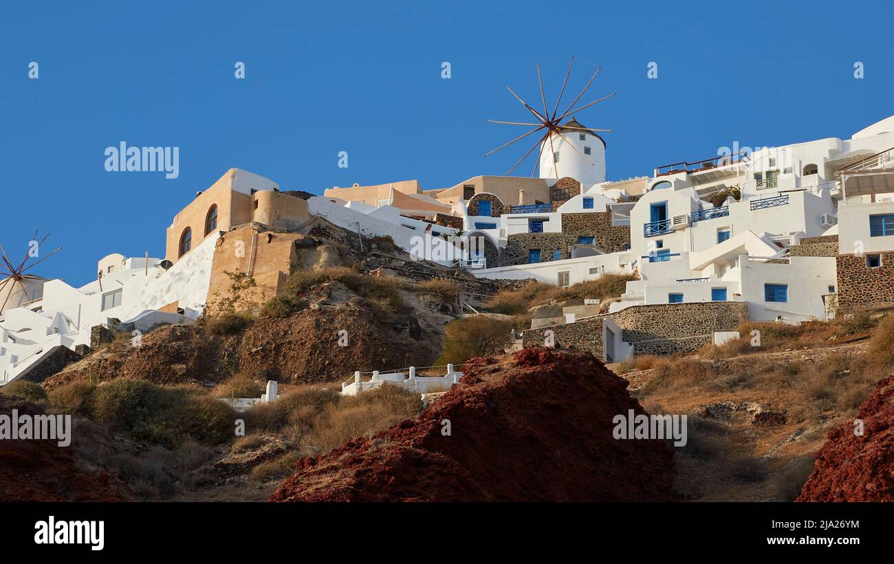 Afternoon light, blue cloudless sky, houses on cliff, windmill, Oia ...