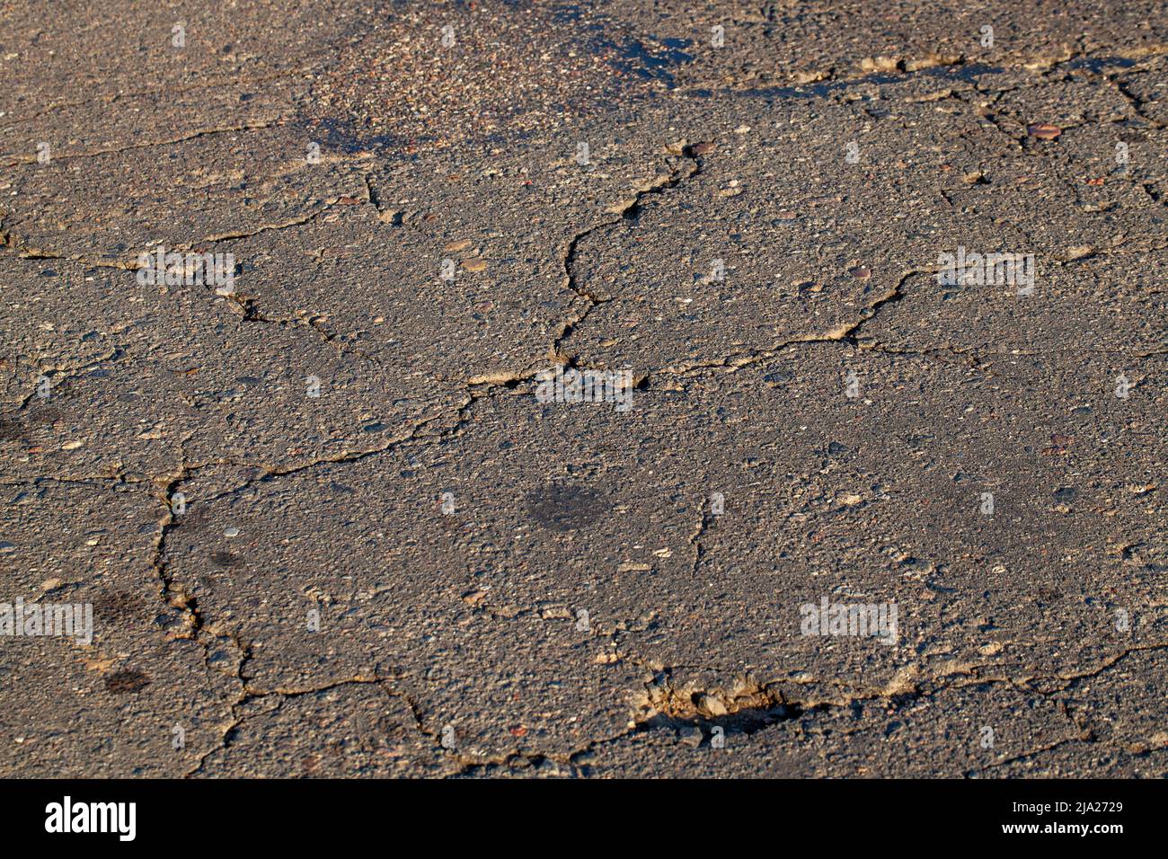 details of an asphalt road with cracks and holes, part of the ...