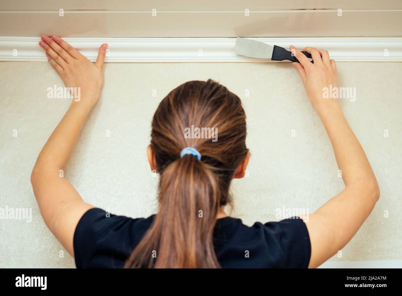 girl (woman) working in a black T-shirt is installing a plinth on the ...