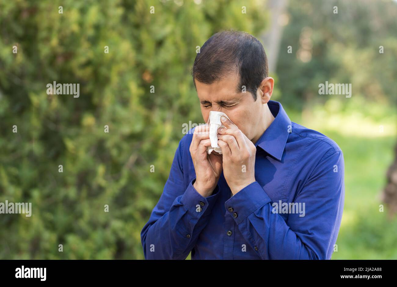 Man blowing in a tissue in a cold winter with a mountain in the ...