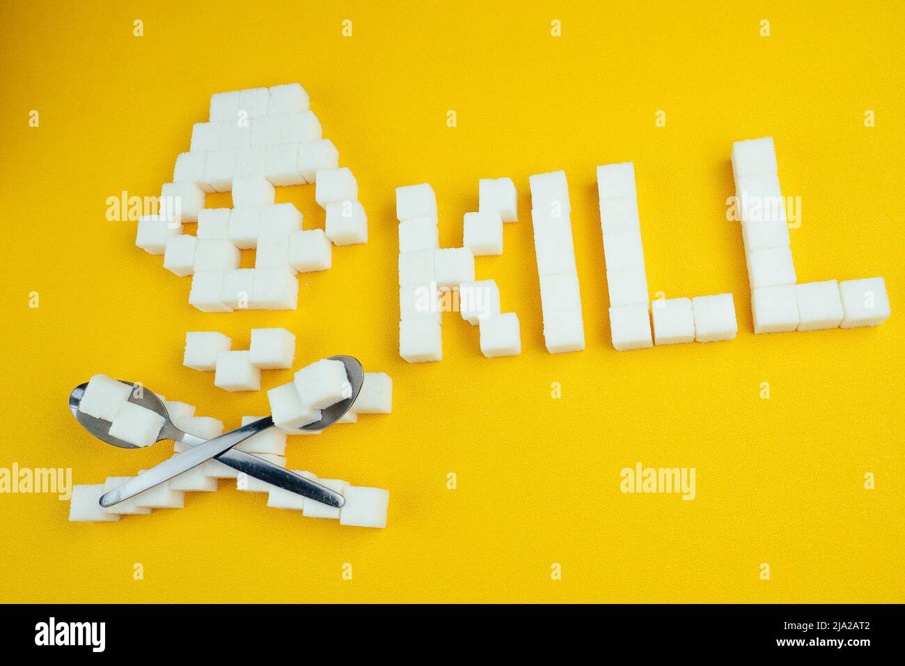 The bones skull made of sugar cubes and dessert spoons on a yellow ...