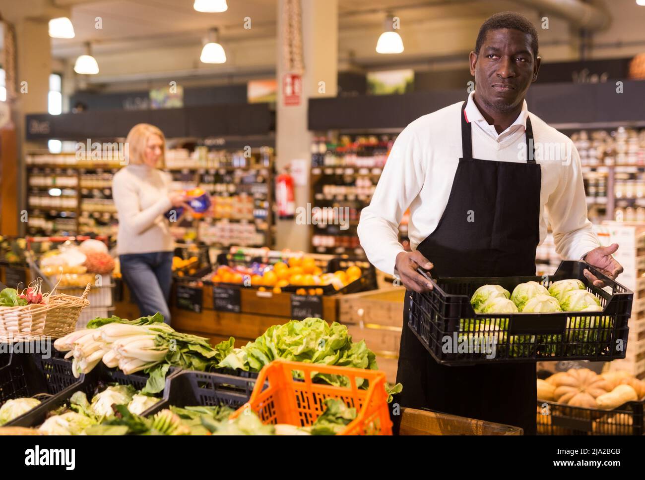 Salesman putting vegetables on store showcase Stock Photo - Alamy