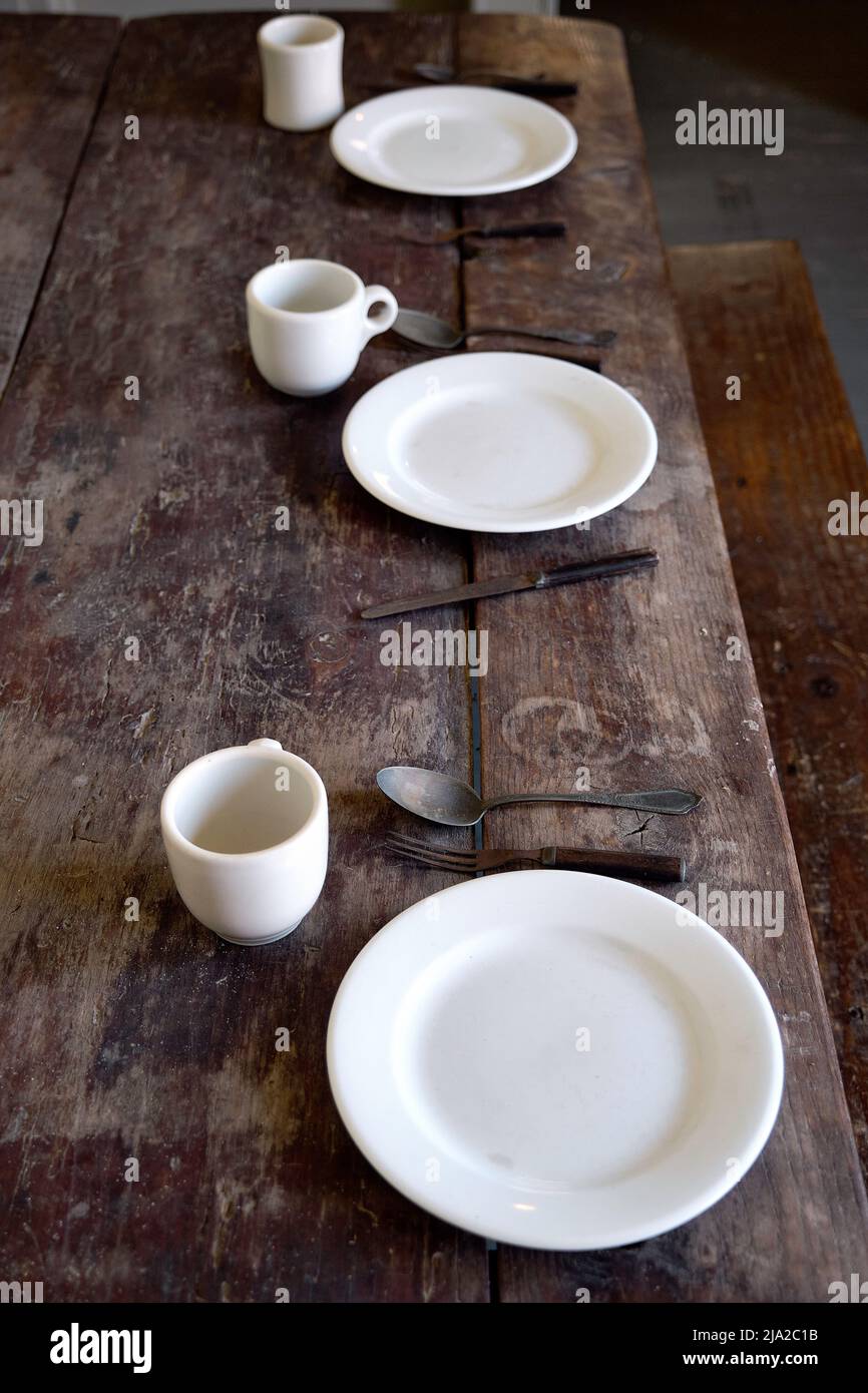 An antique table setting with simple white cups and plates, accompanied ...