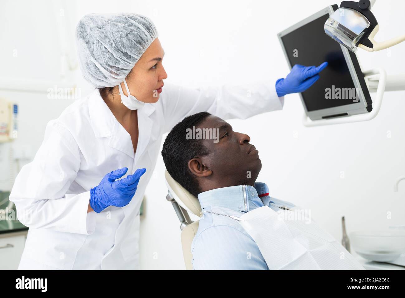 Woman dentist pointing at display to show information to patient Stock ...