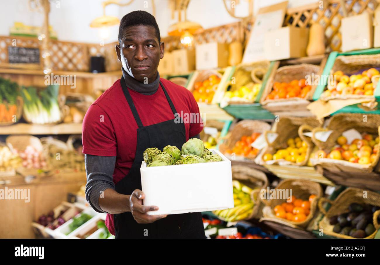 Salesman carrying box with artichokes Stock Photo - Alamy