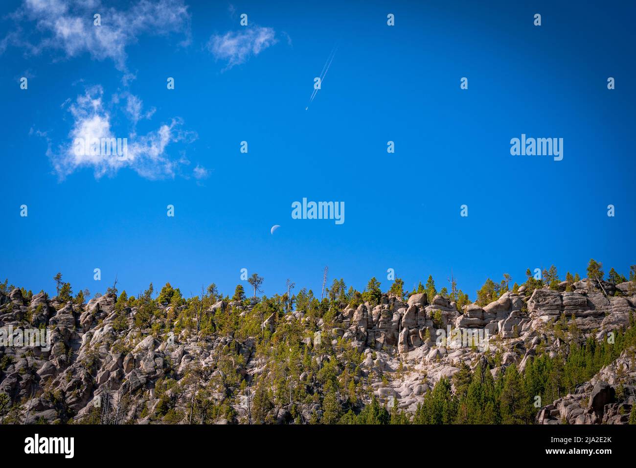 The moon shines in daylight over the mountains in France Stock Photo ...