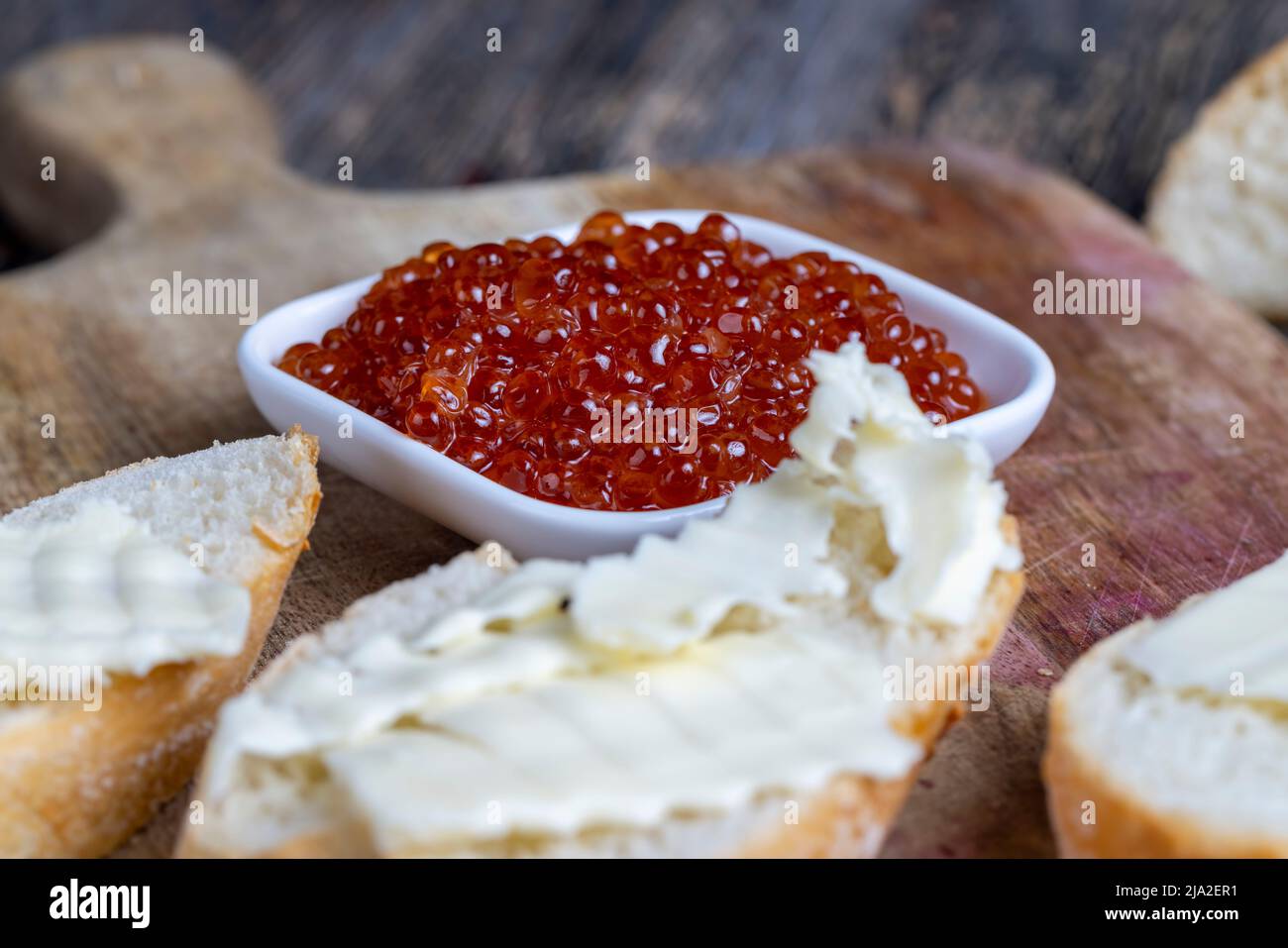 red salmon or trout caviar with white baguette and butter, making ...