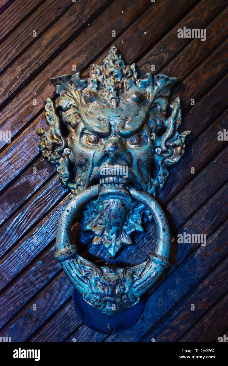 A brass Devil door knocker on a wooden door at the 1926 Medieval-style ...