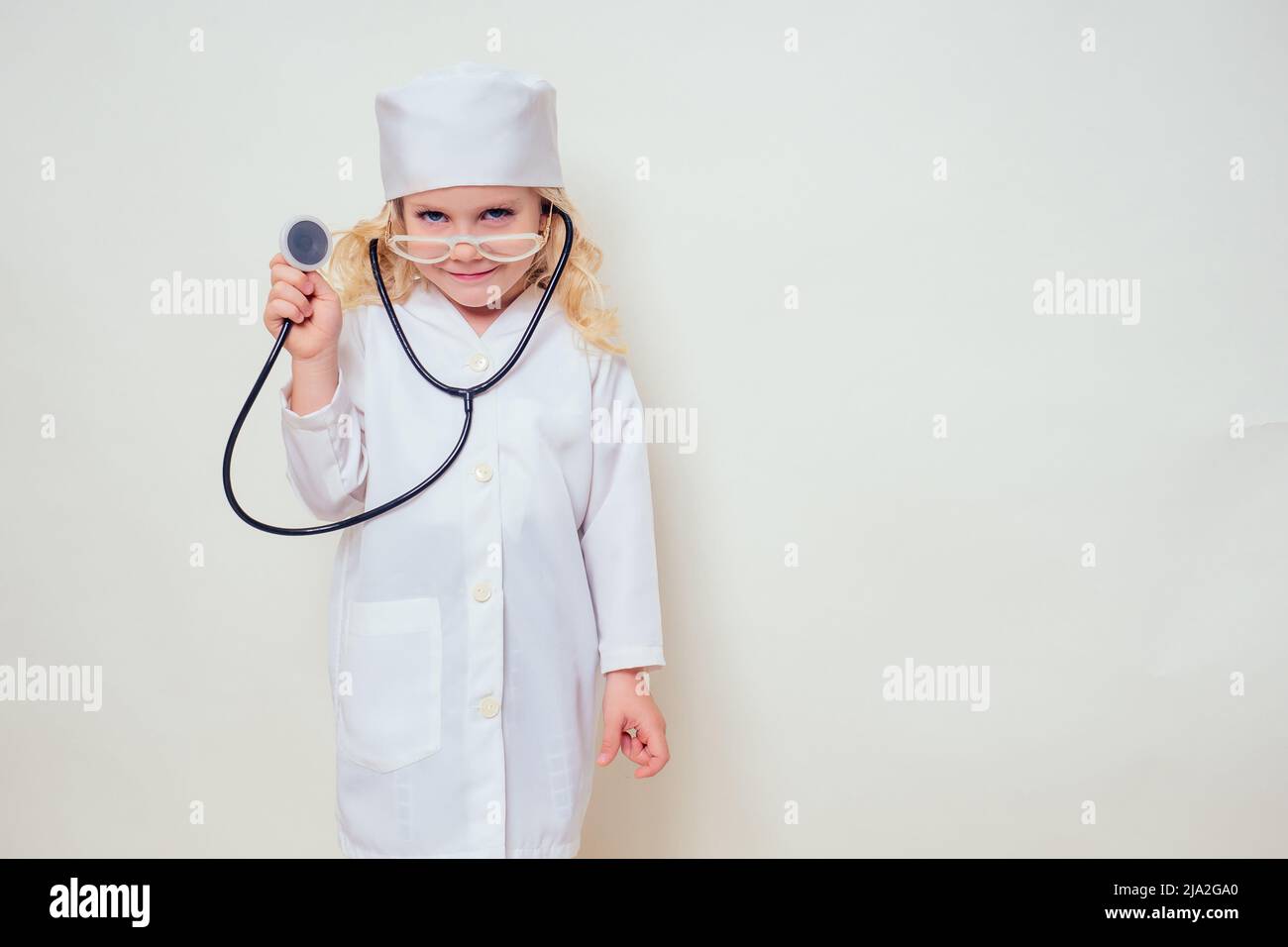Adorable child girl uniformed as doctor wearing doctor's cap and ...