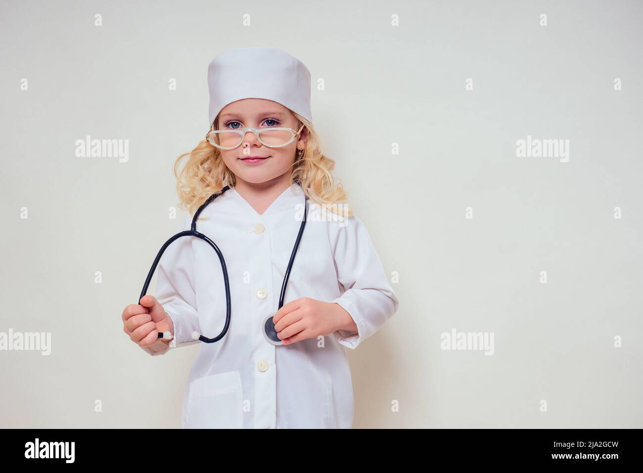 Adorable child girl uniformed as doctor wearing doctor's cap and ...